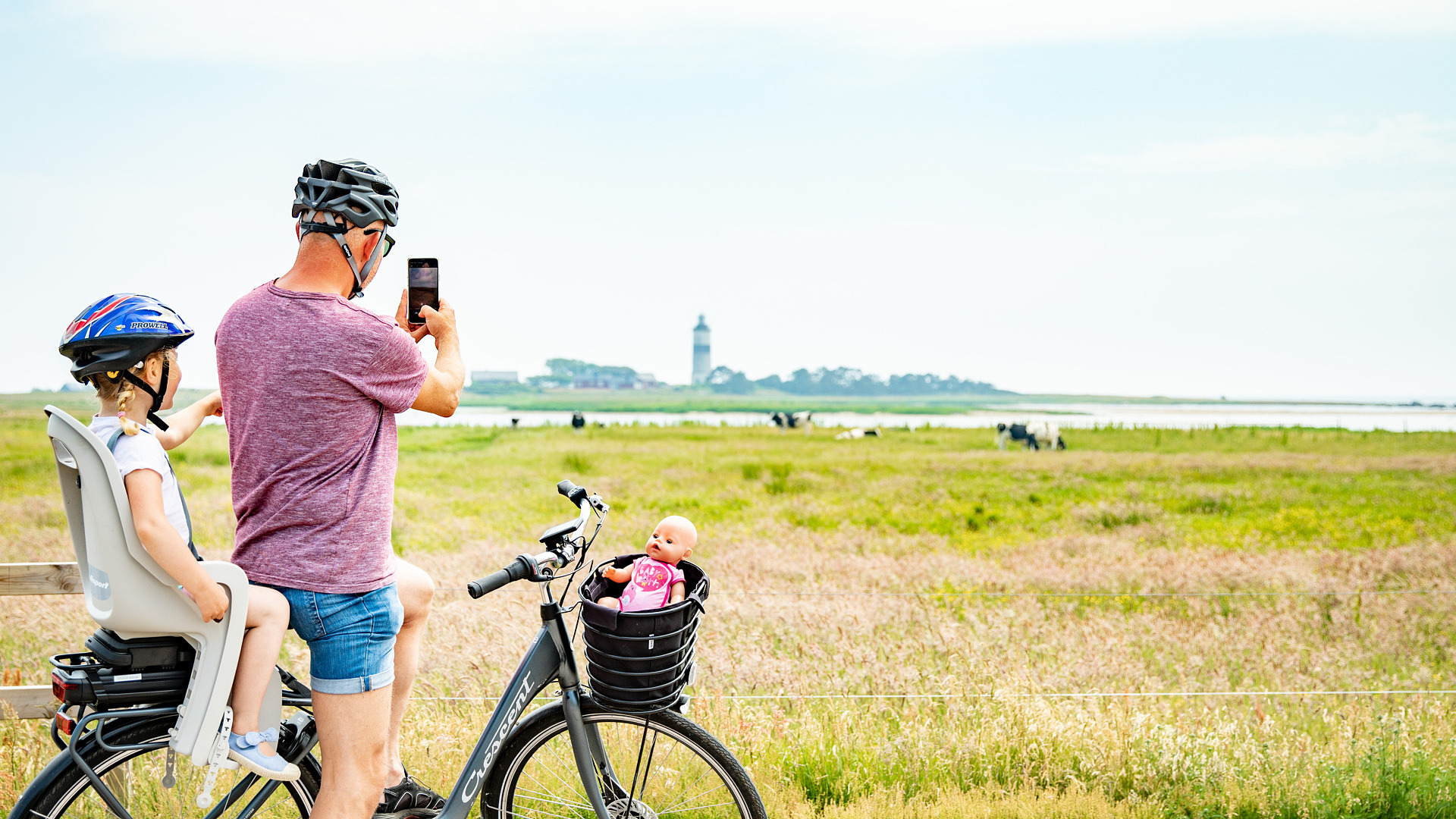 En man har stannat sin cykel och tar ett kort med mobilen på en fyr och ...